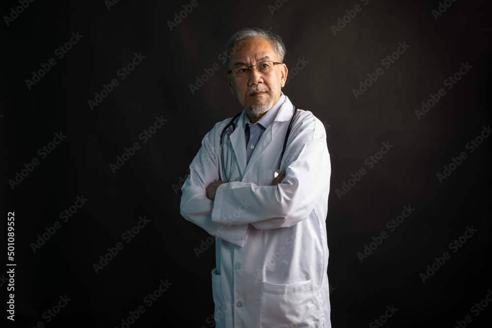 Asian senior doctor man standing and cross arm on black background ...