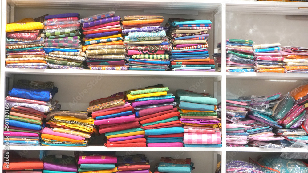 Colorful sarees or saris are arrange on racks and display in a retail ...