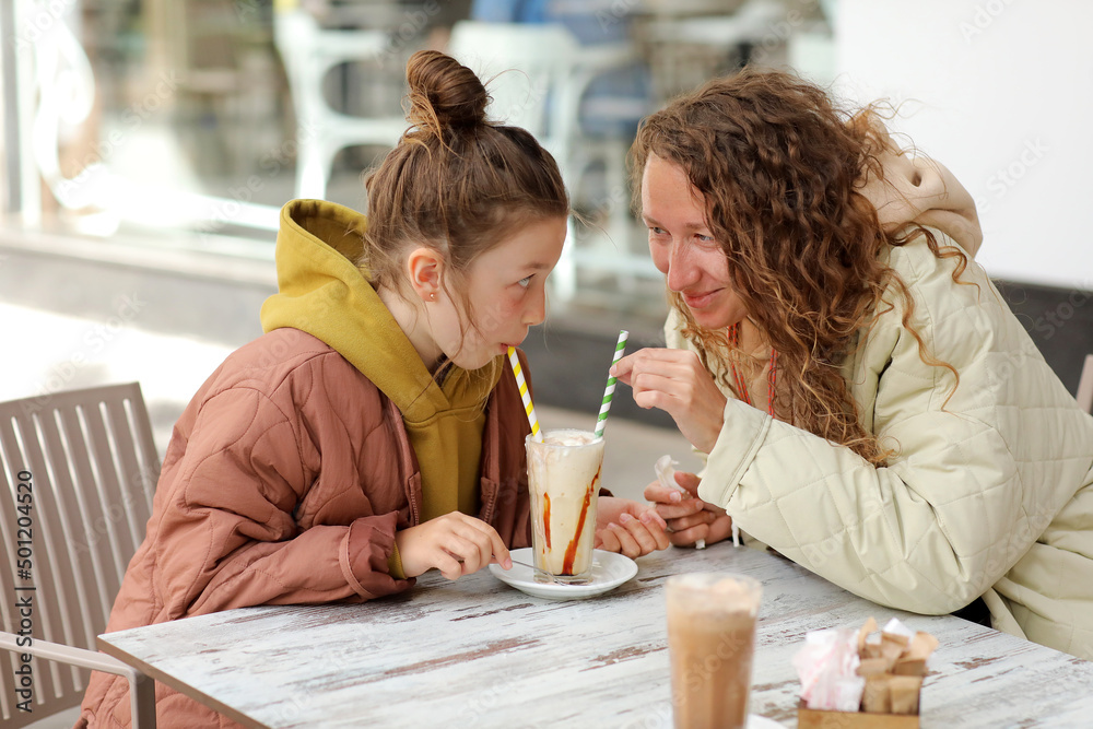 Happy mother and her adorable teen daughter at outdoors cafe drinking ...