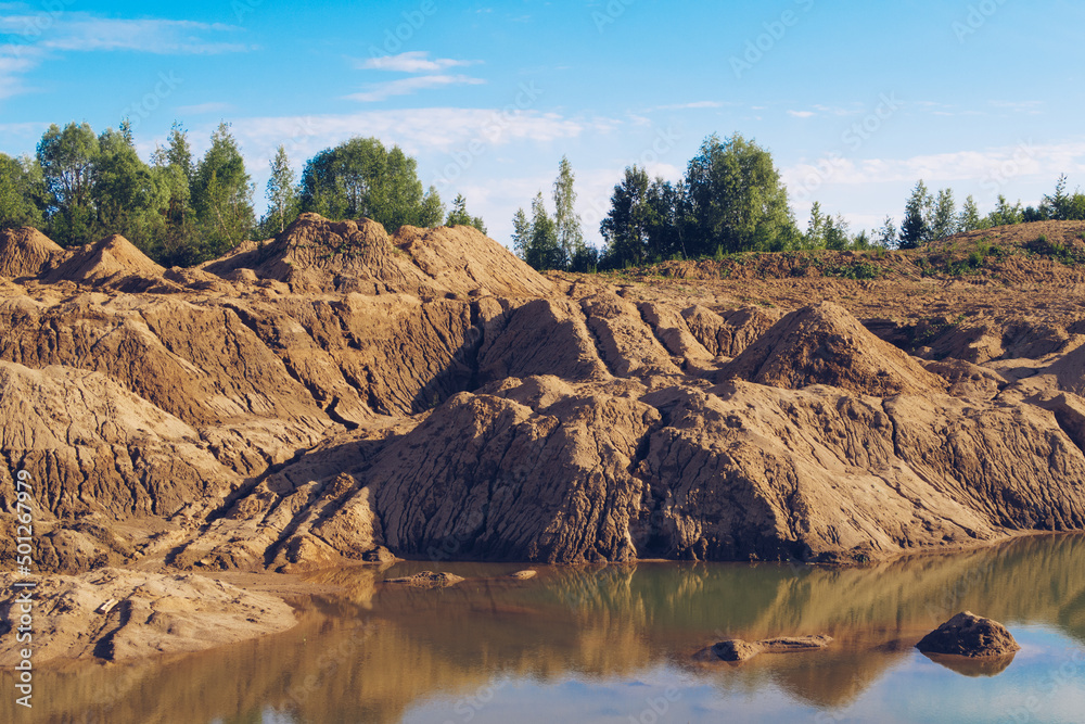 Flooded sand quarry. Cracked drought clay piles during the dry season ...