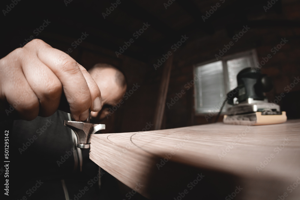 Carpenter with hand electric router machine at work. Trying on a cutter ...