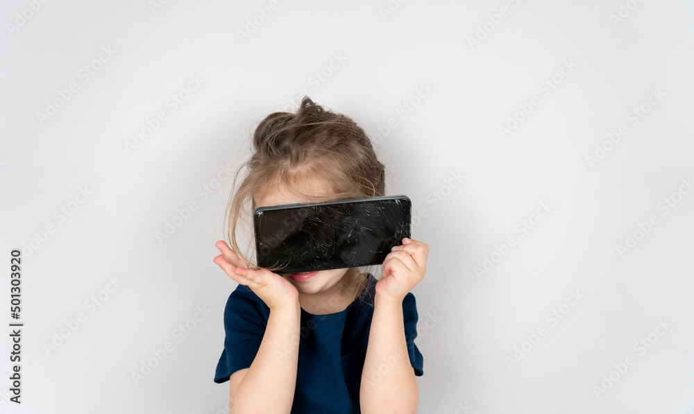 Portrait of terrified child with damaged phone. Upset little girl ...