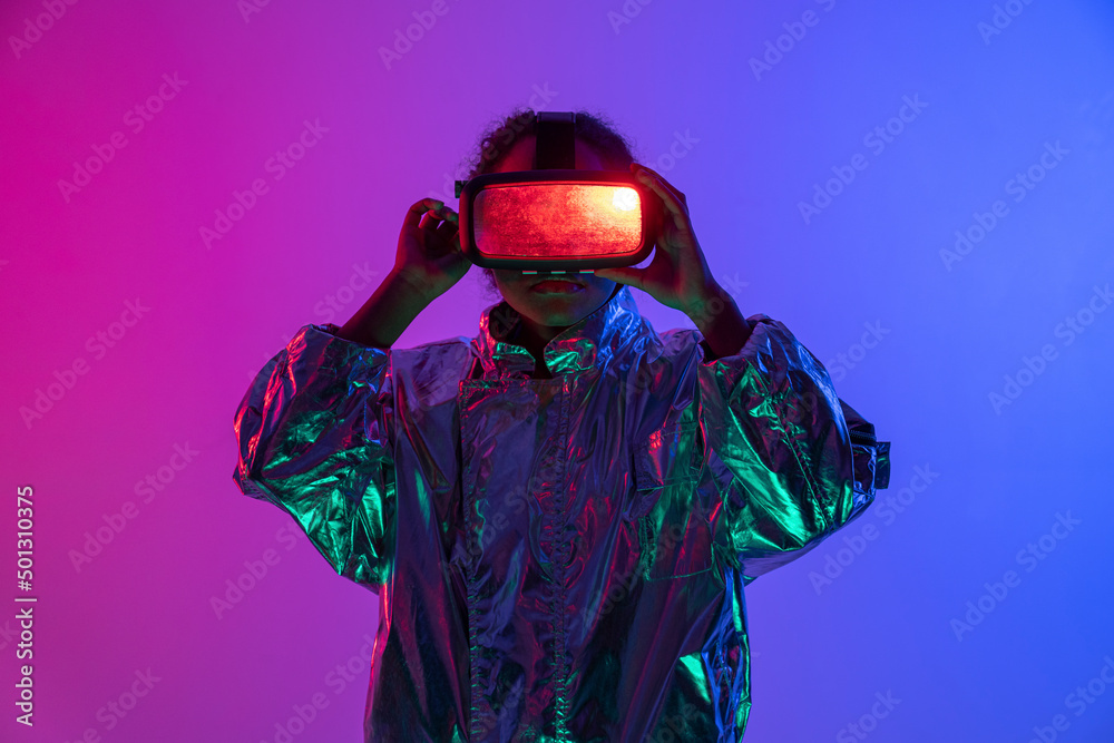 Woman wearing virtual reality simulator standing against multi-colored ...