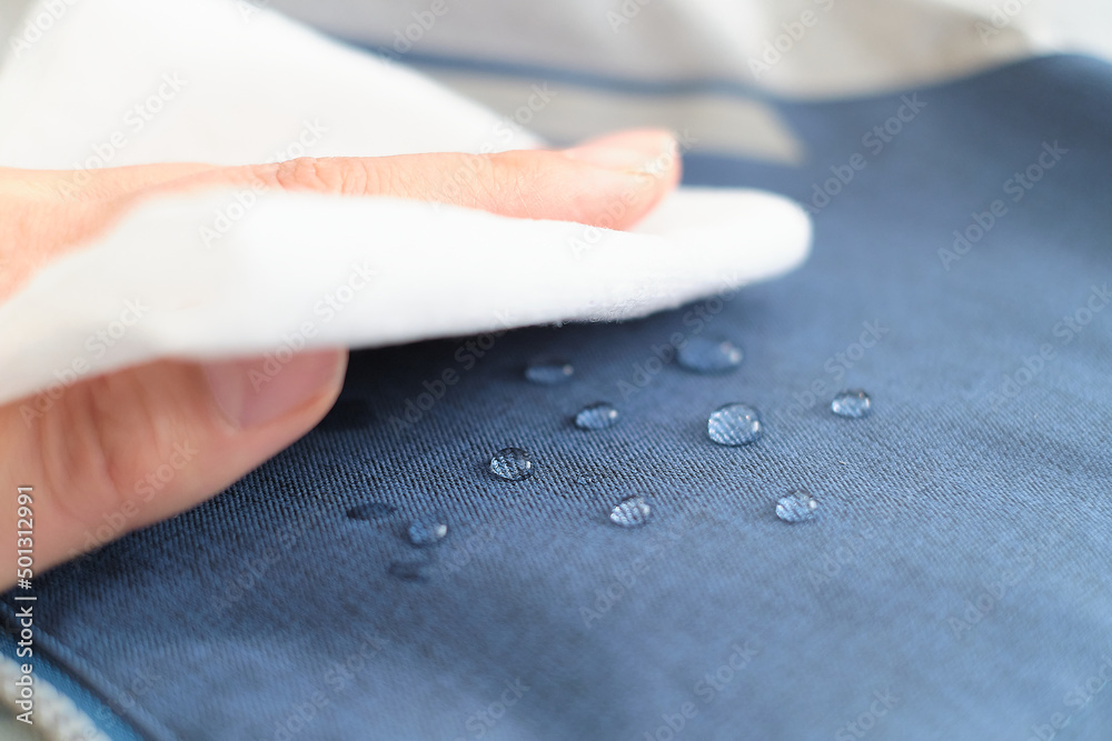 hand wipes drops of water from a cloth. Water drops on waterproof ...