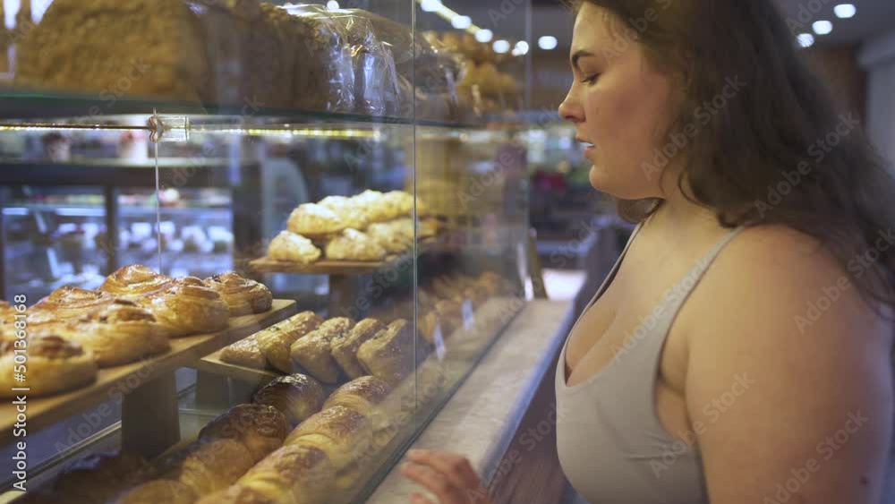 Overweight girl comes to showcase with bakery of the supermarket and ...