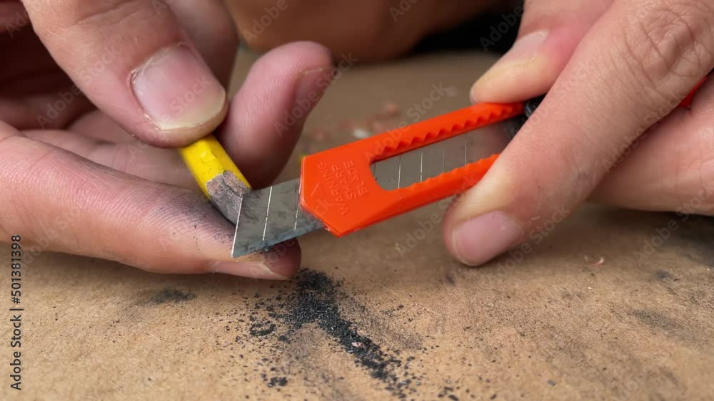 Male hand artist sharpening pencil with a sharp blade box cutter knife ...