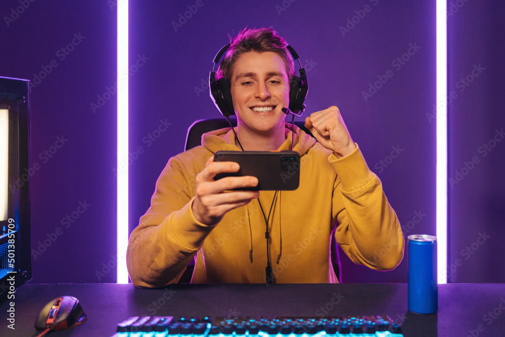 Playing video games on smartphone. Young caucasian handsome man sitting ...