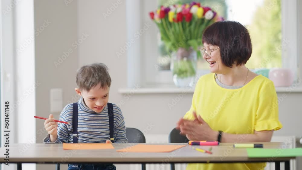 Medium shot intelligent pedagogue clapping supporting autistic boy ...