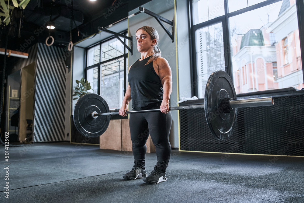 Fit midget woman lifting barbells and looking focused, while working ...