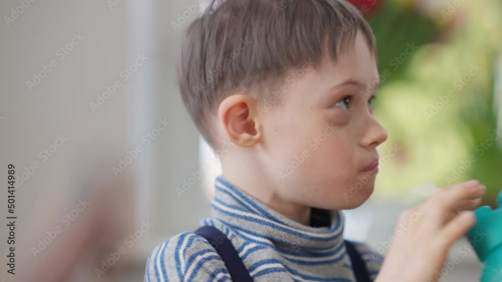 Headshot portrait of cute autistic boy drinking juice passing bottle ...