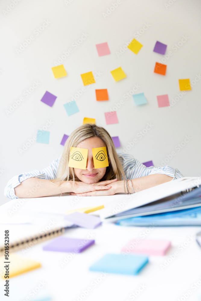 Business woman sits behind her desk on which are many office things and ...