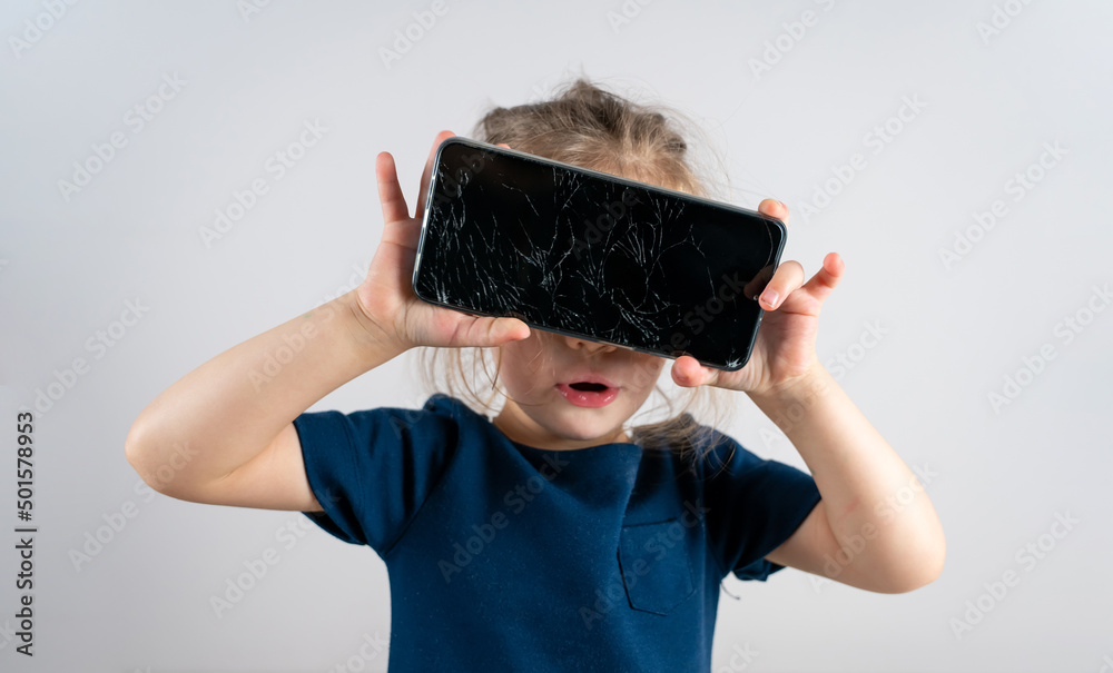 Portrait of terrified child with damaged phone. Upset little girl ...