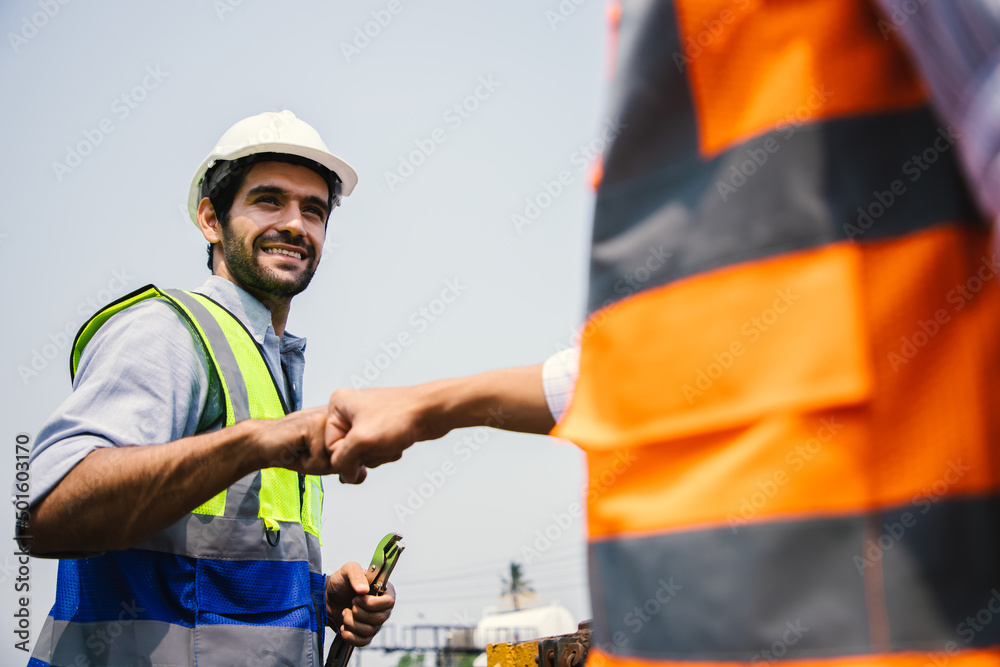 Engineers working on train garage site and holding hands to fist bump ...