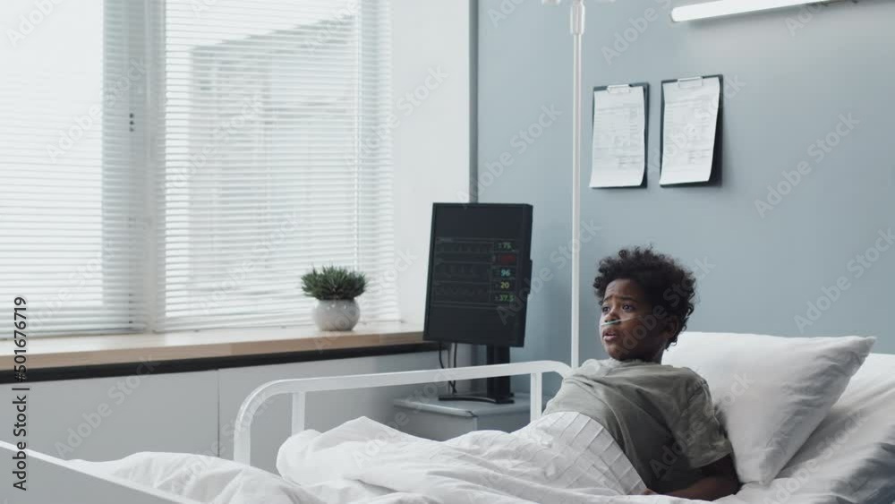 Medium long of Black boy with oxygen tube in nose sleeping in hospital ...
