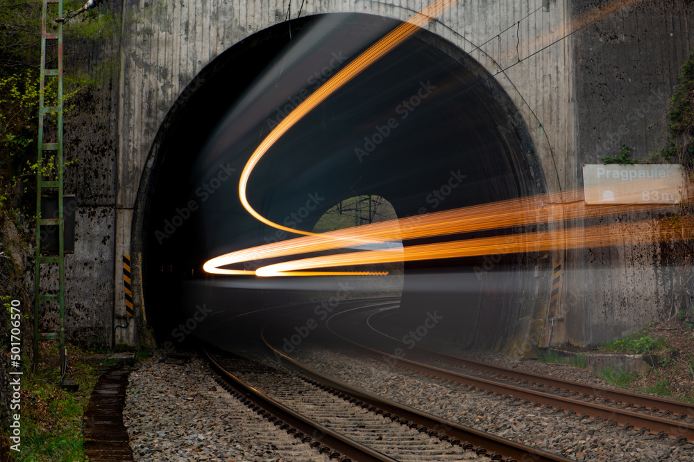 Fast train coming to light out of a tunnel with old concrete portal ...