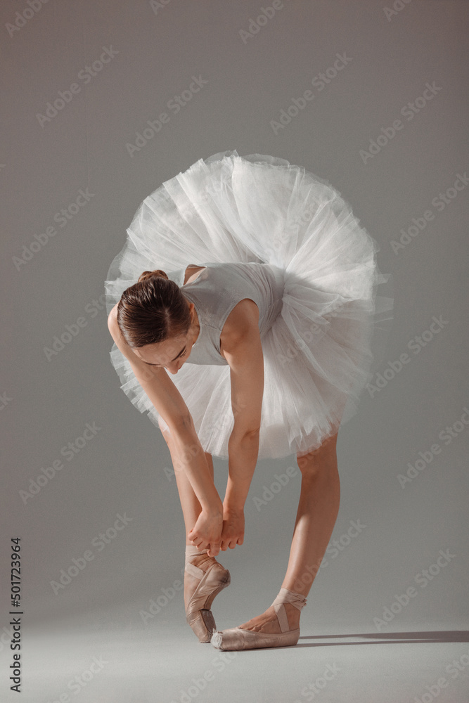 ballet posing. young slim dancer, brunette girl ballerina is tying ...