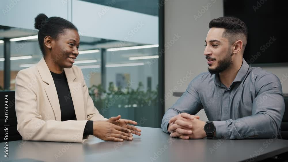Arabic businessman and African businesswoman talking at office table ...