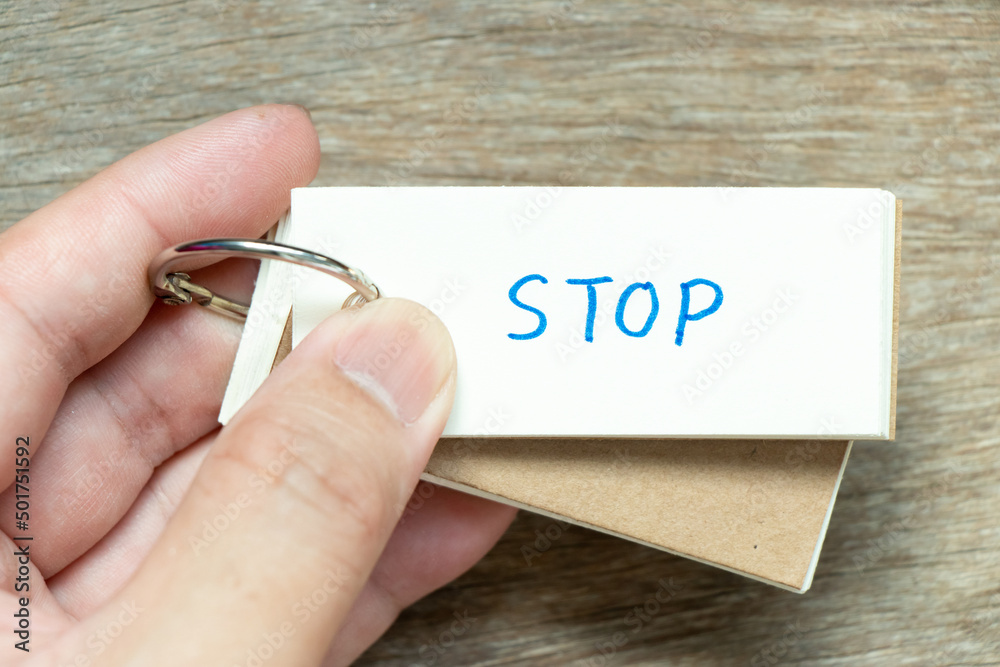 Man hold the flash card with handwriting word stop on wood background ...