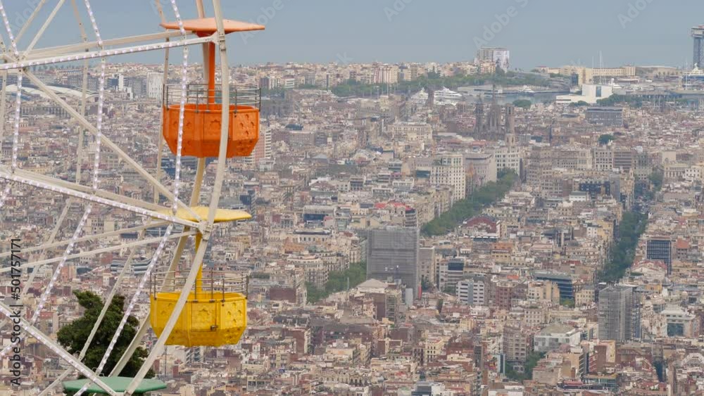 Empty gondolas of carousel wheel move against dense build city seen ...