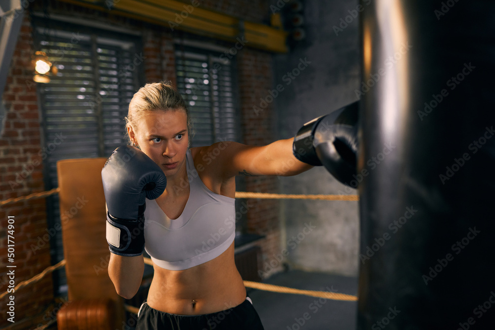 Horizontal medium shot of young woman with hands in boxing gloves ...