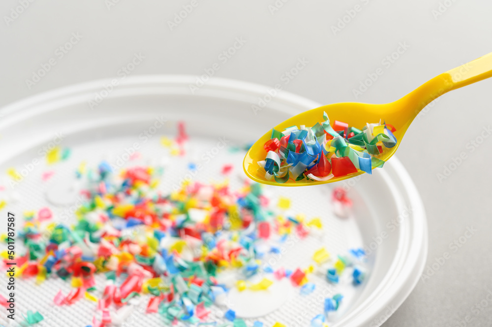 Microplastic in white plastic dish with spoon. Light grey background ...