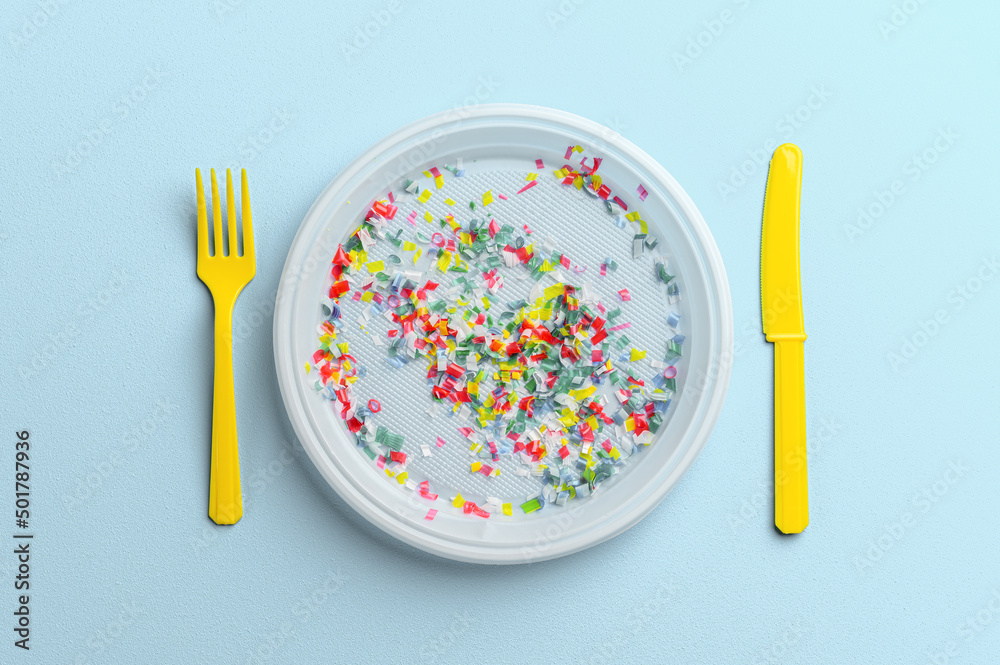 Microplastic in white plastic dish with knife and fork. Pastel blue ...