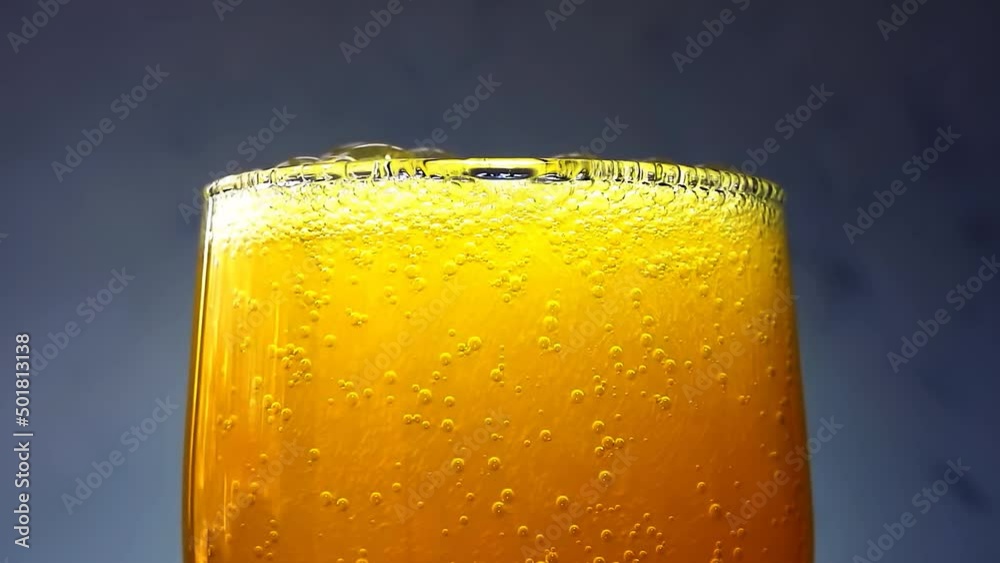 Orange soda is pouring into a glass close-up on a grey background ...