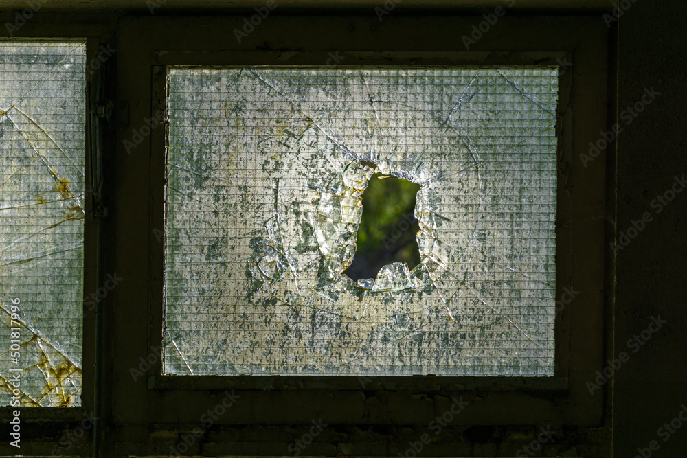 Detail of broken window looking outside of an empty industrial building ...