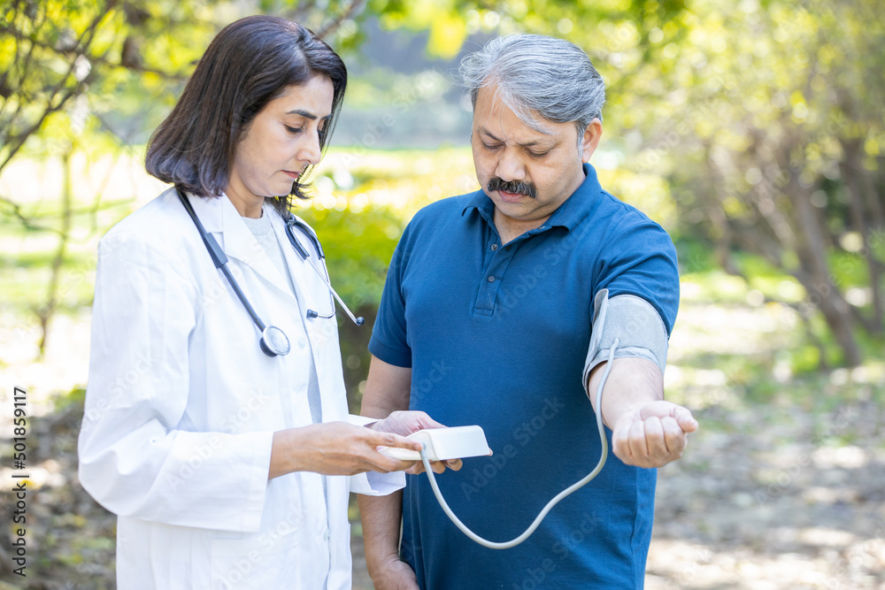 Mature female nurse measure high blood pressure of sick mature male ...