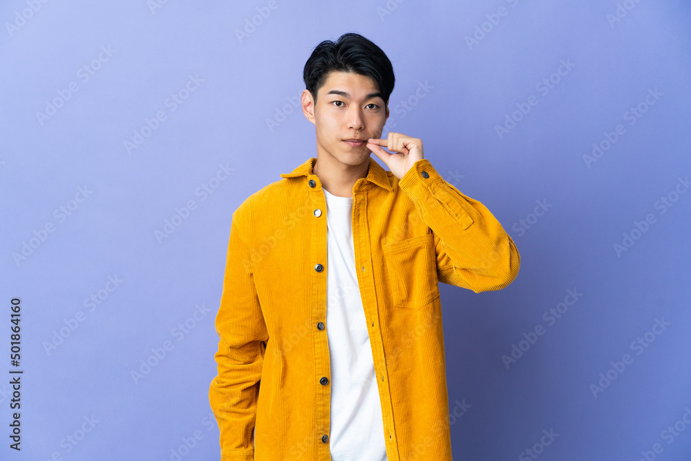 Young Chinese man isolated on purple background showing a sign of ...