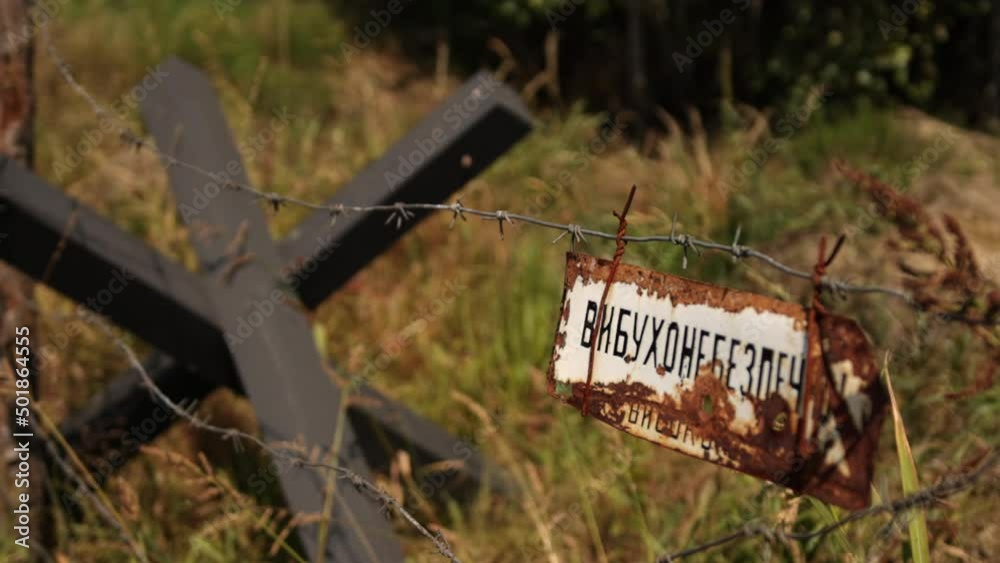 Translation: Explosive. Rusty anti-tank hedgehogs on grass in forest ...