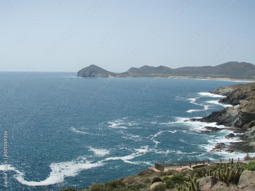 Mar con espuma en primer plano y rocas de borde de costa y al fondo ...