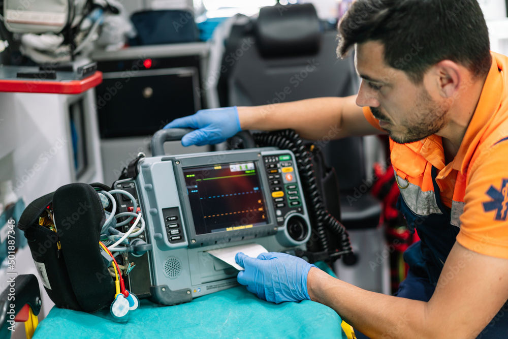 portrait of a handsome young paramedic working with a defibrillator ...