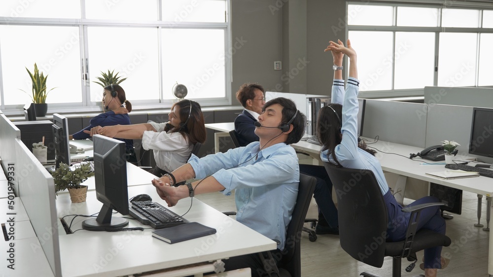 Call center is tired, young adult employee working with headset stretch ...