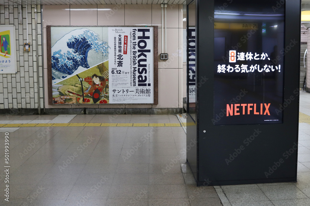 TOKYO, JAPAN - May 1, 2022: Screens advertsing Netflix and a poster ...