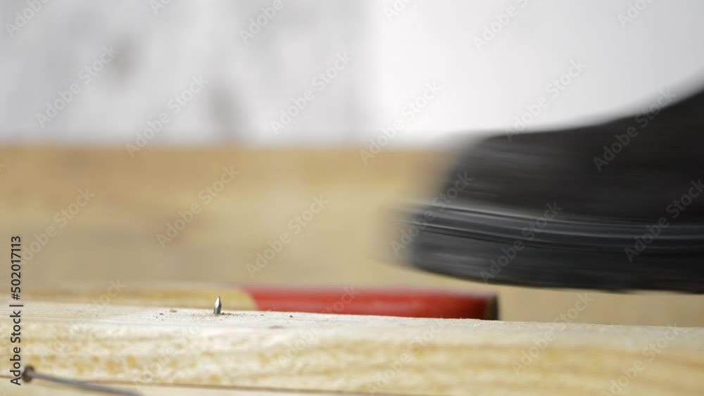 Close-up of man's foot stepping over there nail inserted in wooden ...