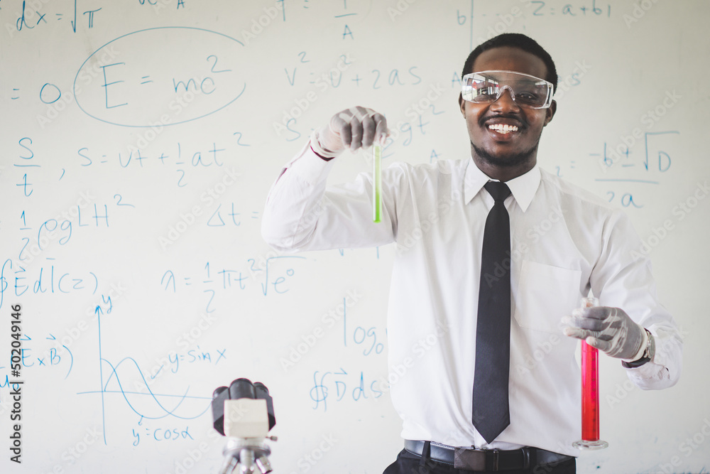 African science teacher conducting experiment mixing liquids in flask ...