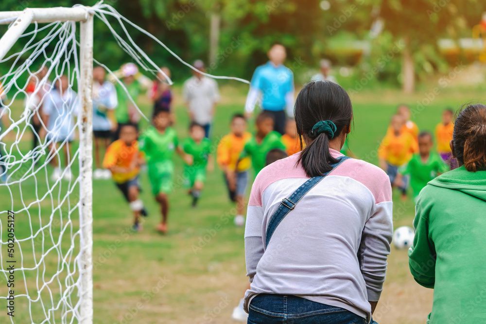 Back view of Moms watch and cheering their sons playing football in ...