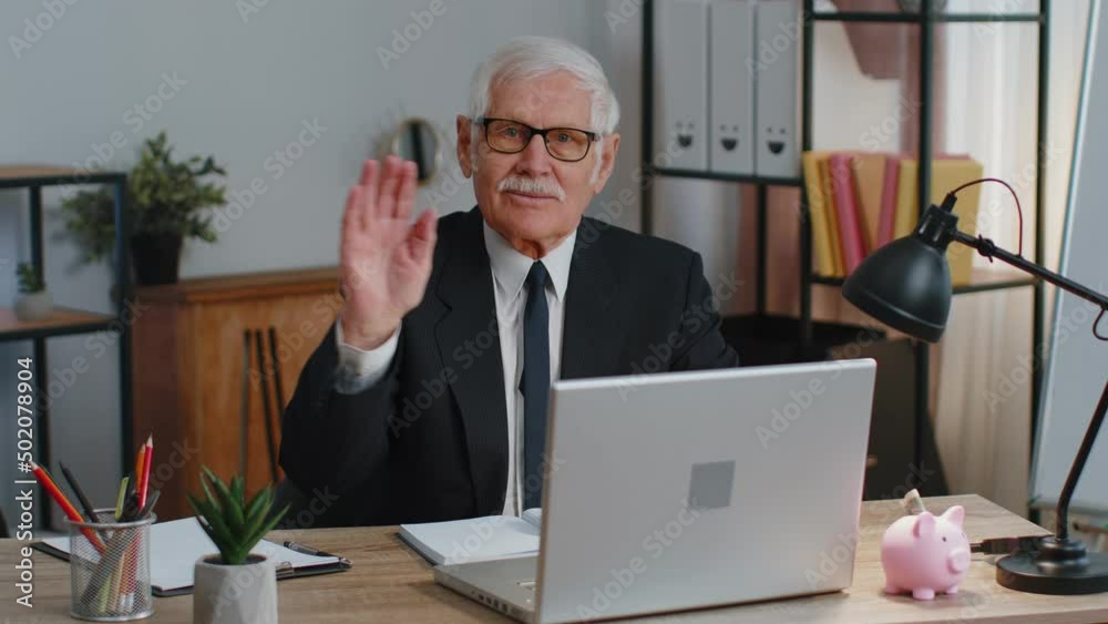 Hello. Senior business man employee wears glasses waves hand palm in hi ...