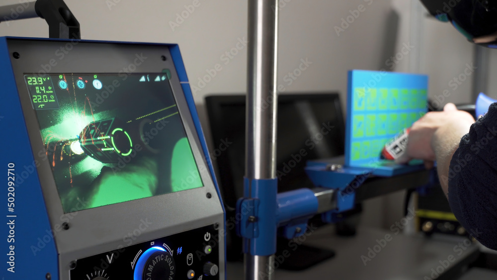 Close up of an engineer using modern welding equipment and a computer ...