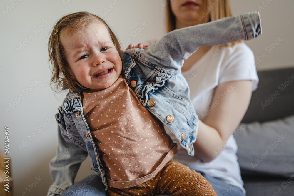 Small caucasian baby girl infant child with her mother dressing ...