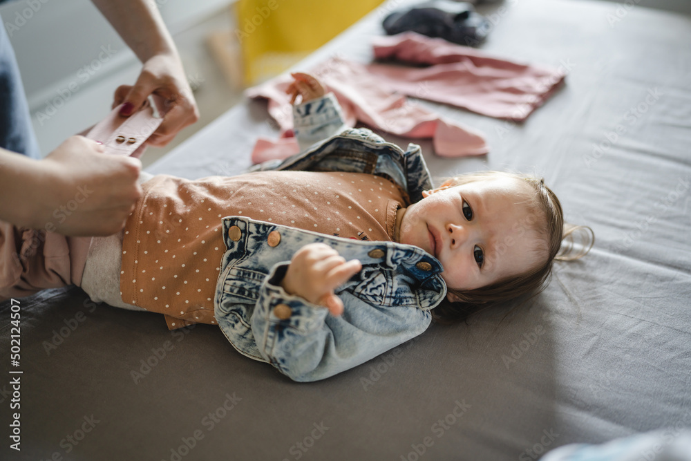Small caucasian baby girl infant child with her mother dressing or ...