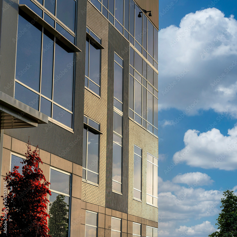 Square White puffy clouds Building facade with bricks, glass and ...