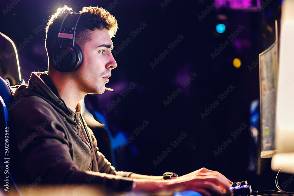 Profile of a professional gamer playing video games in dark gaming room ...