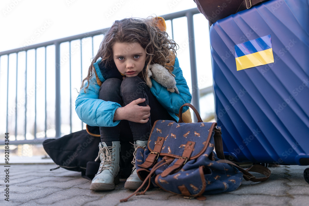 Sad Ukrainian immigrant child with luggage waiting at train station ...