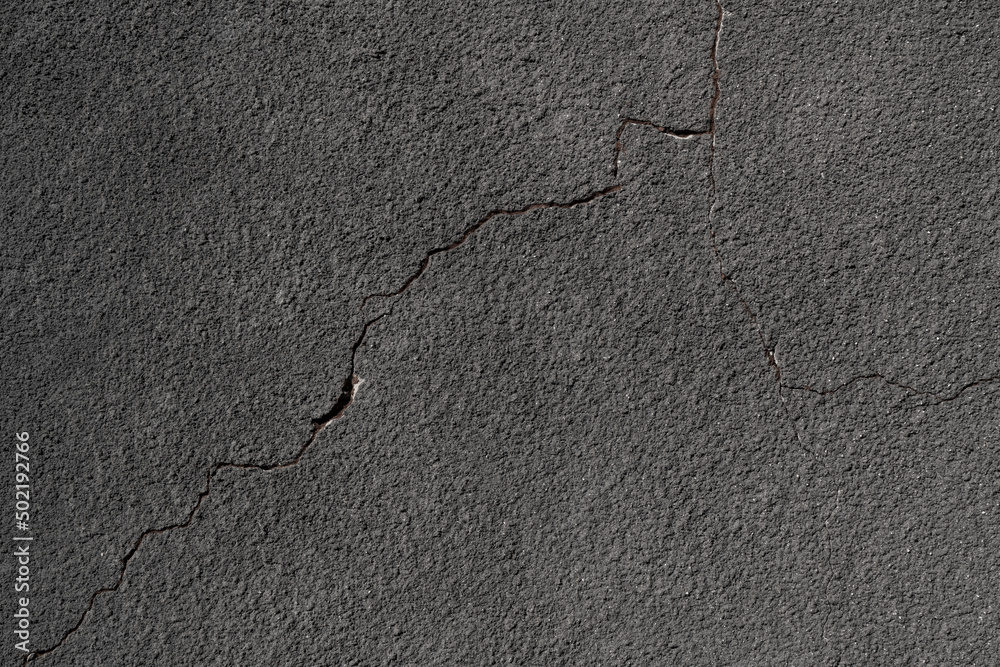 Gray wall with a crack. Texture of rough plaster with uneven granular ...