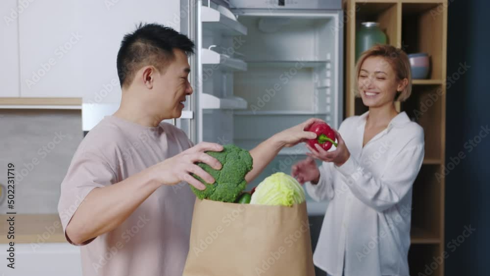 Sweet multi-ethnic couple in love coming back after shopping in kitchen ...
