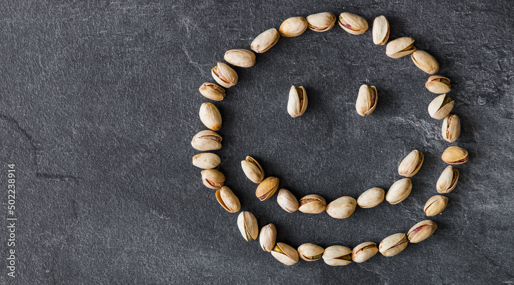 Smiley smiling with pistachios on a black background. The concept of ...