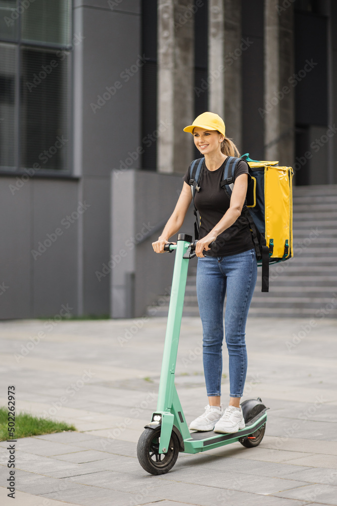 Food delivery female courier rides electric scooter to deliver orders ...