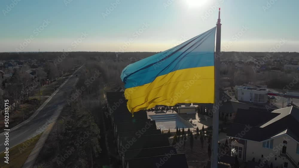 Aerial orbiting shot showing Ukrainian flag waving in the wind against ...